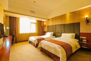 Quarto de hotel com duas camas, uma mesa e uma janela grande com cortinas.