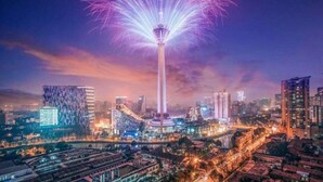 Paisagem urbana com uma torre imponente e fogos de artifício.