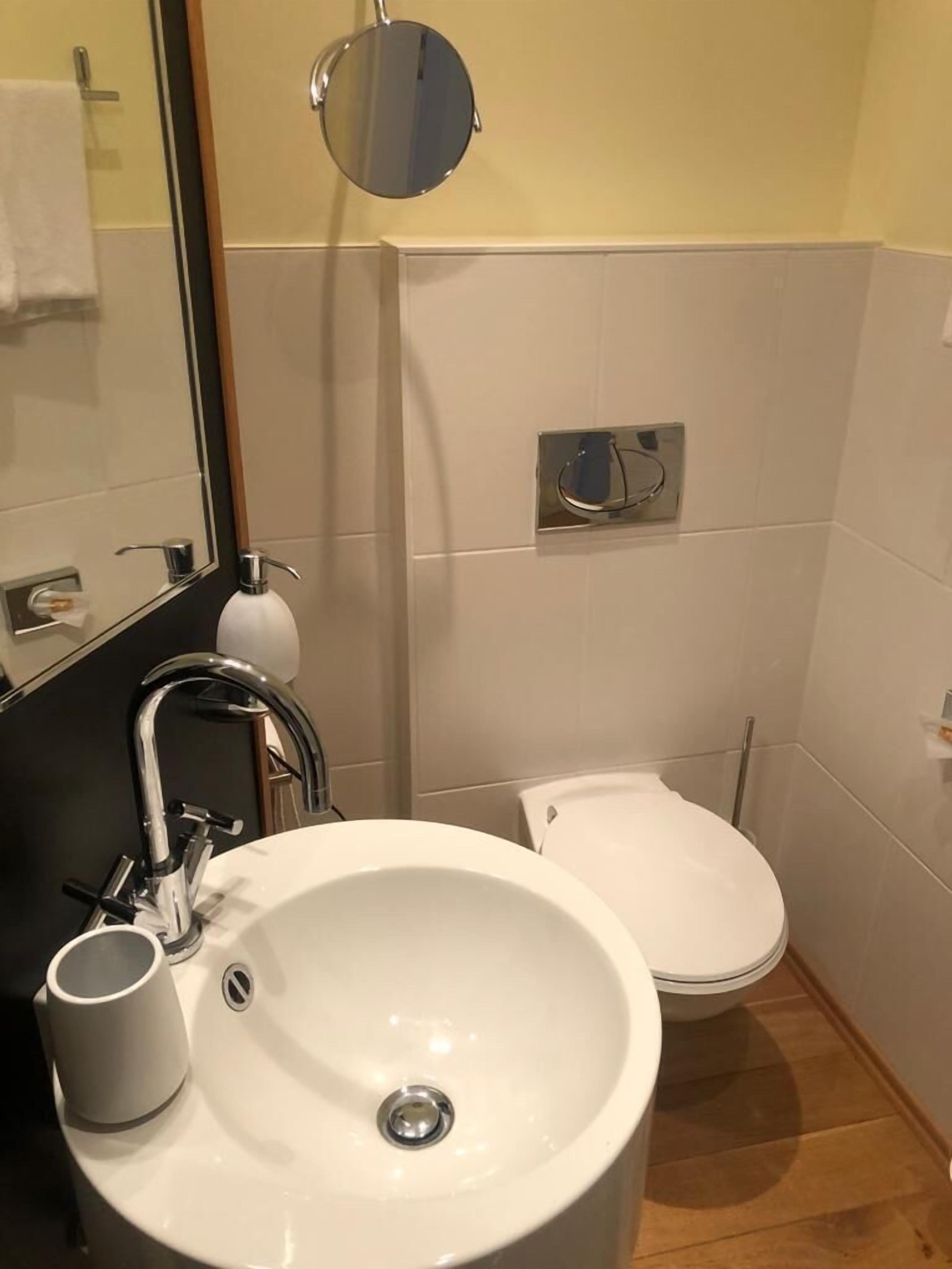 Um banheiro compacto com pia branca, vaso sanitário e espelho.