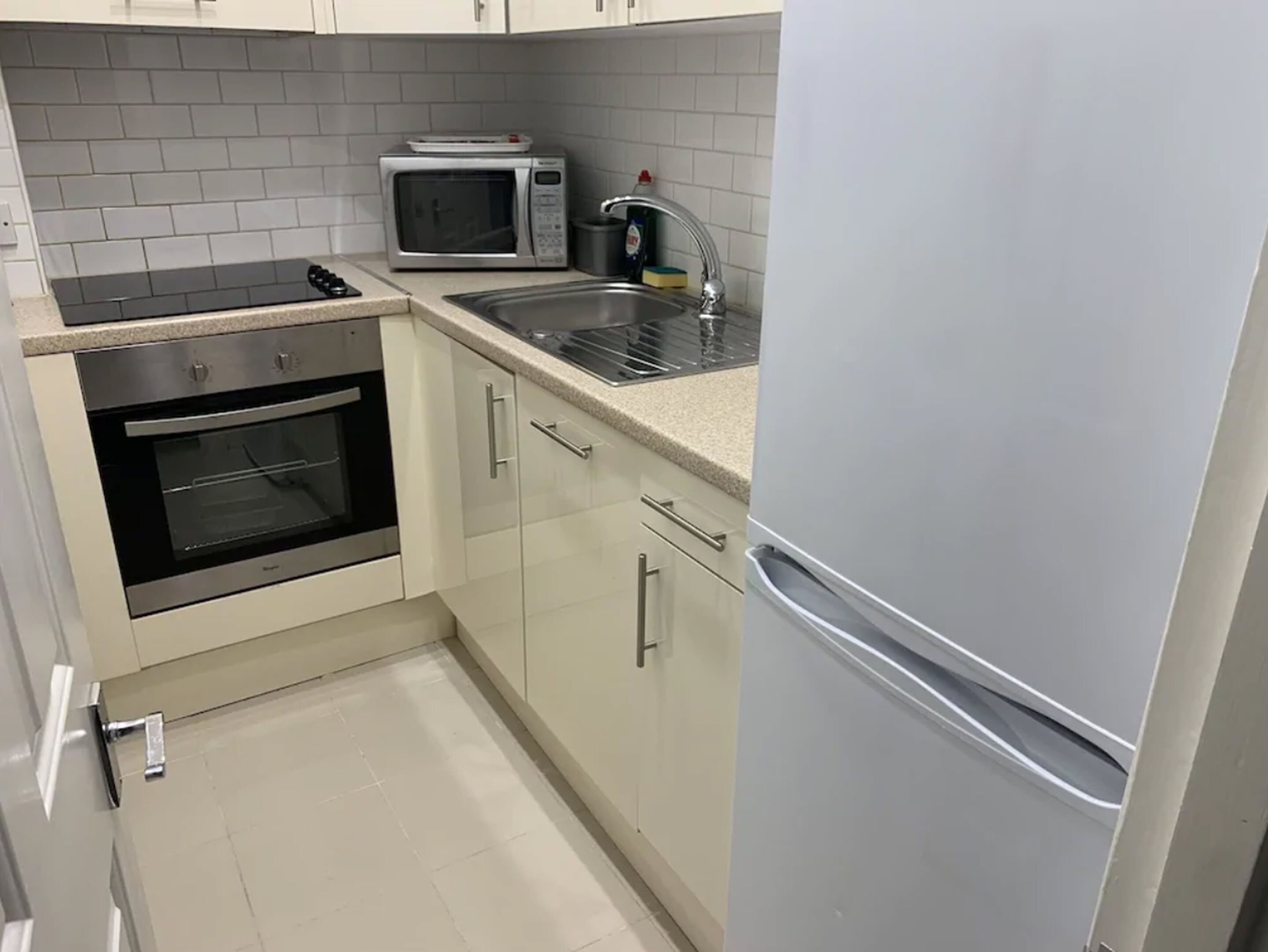 Cozinha com forno embutido, micro-ondas e geladeira de aço inoxidável.