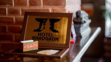 Um letreiro emoldurado com o texto 'HOTEL BHADGAON' em cima de um balcão.