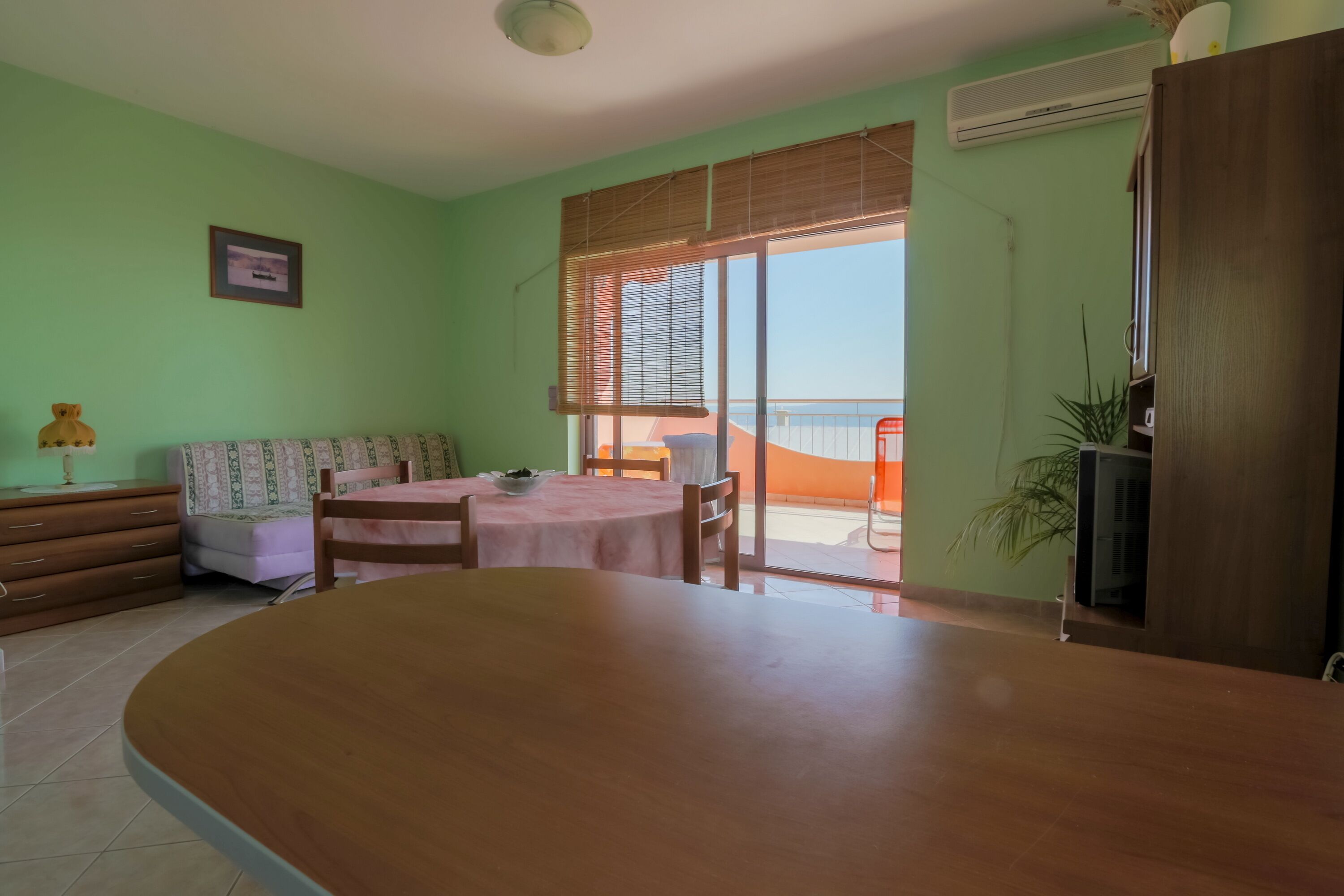 Quarto com mesa de jantar, cadeiras, sofá, armário de madeira e janela com persianas.