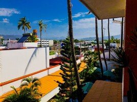 Varanda com vista para um horizonte urbano, incluindo edifícios e palmeiras.