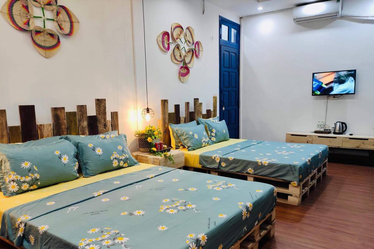 Quarto com duas camas, televisão e escrivaninha de madeira.