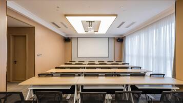 Uma sala de conferências com uma mesa comprida, cadeiras, um projetor e um amplo janelão com cortinas.