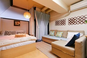 Um quarto com uma cama, um sofá, uma mesinha e um objeto decorativo na parede.