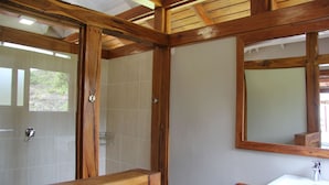 Casa de banho com toucador de madeira, lavatório branco e um espelho grande.