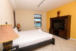Quarto de hotel com cama, televisão, janela com vista e luminária.