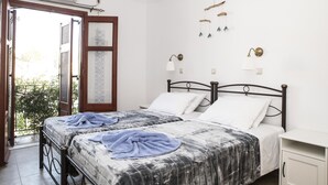 Quarto com duas camas, uma janela e uma mesinha de cabeceira.