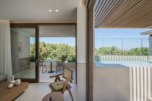 Varanda moderna com porta de vidro que dá para área de estar com mesa e cadeiras, com vista para paisagem verde exuberante.