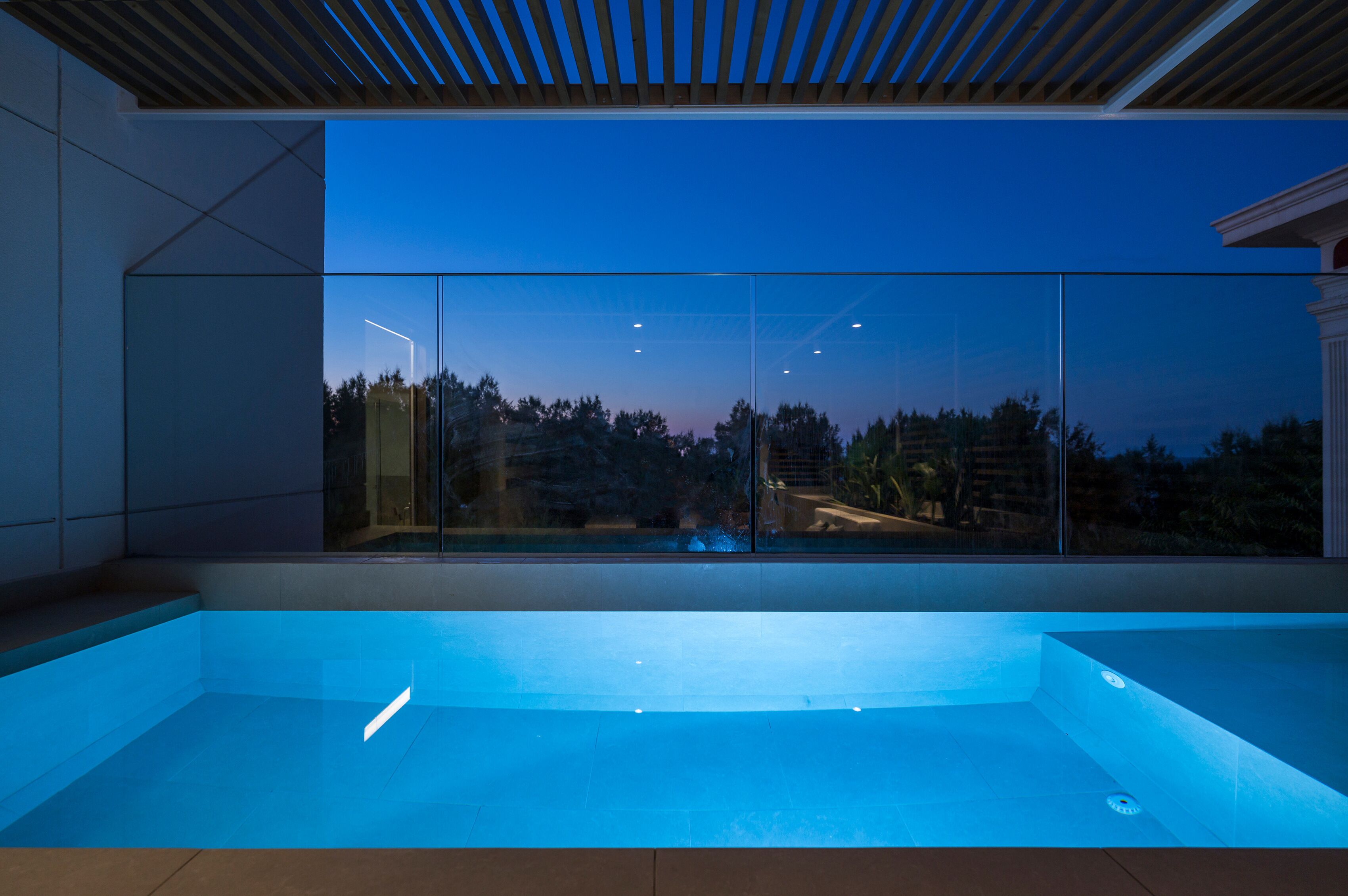 Piscina interior moderna com parede de vidro que oferece vista da paisagem e edifícios ao redor.