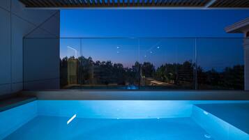 Piscina interior moderna com parede de vidro que oferece vista da paisagem e edifícios ao redor.