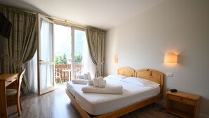Quarto com cama de madeira, uma escrivaninha e mesa de cabeceira.