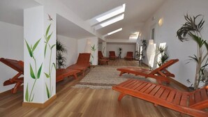 Um quarto espaçoso com piso de madeira, várias poltronas de descanso e um claraboia.