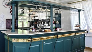 Uma área de bar com balcão, prateleiras com copos e uma máquina de café.