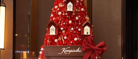 Decoração de Natal com uma árvore vermelha, uma loja chamada "Kempinski" e várias enfeites festivos.