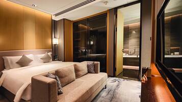 Quarto de hotel moderno com uma cama grande, um sofá, um closet espaçoso e um banheiro com banheira.
