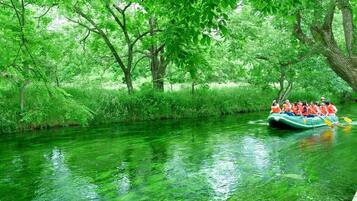Um grupo de pessoas em um bote inflável verde em um rio, cercado por vegetação exuberante.