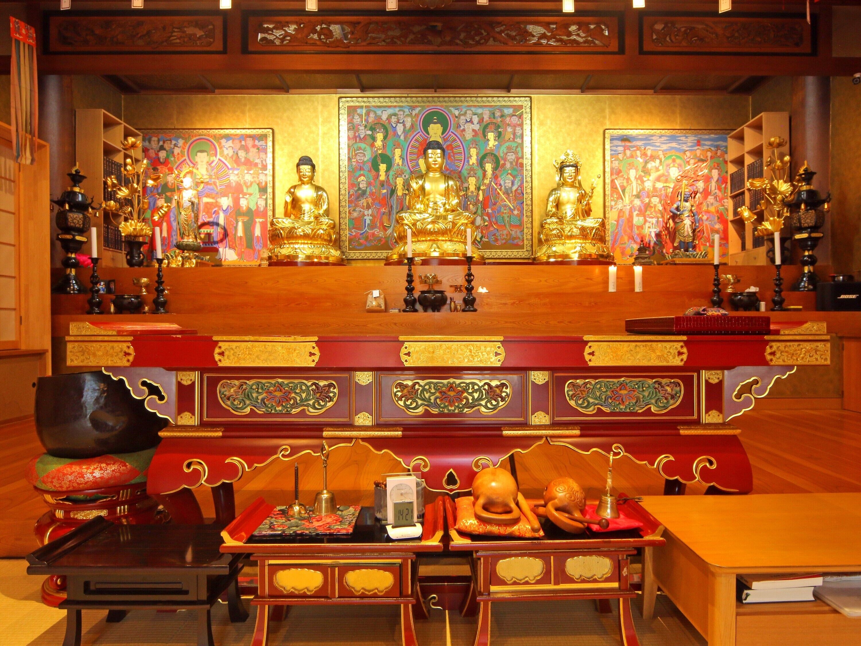 Quarto tradicional com altar de madeira, estátuas douradas e pinturas religiosas.
