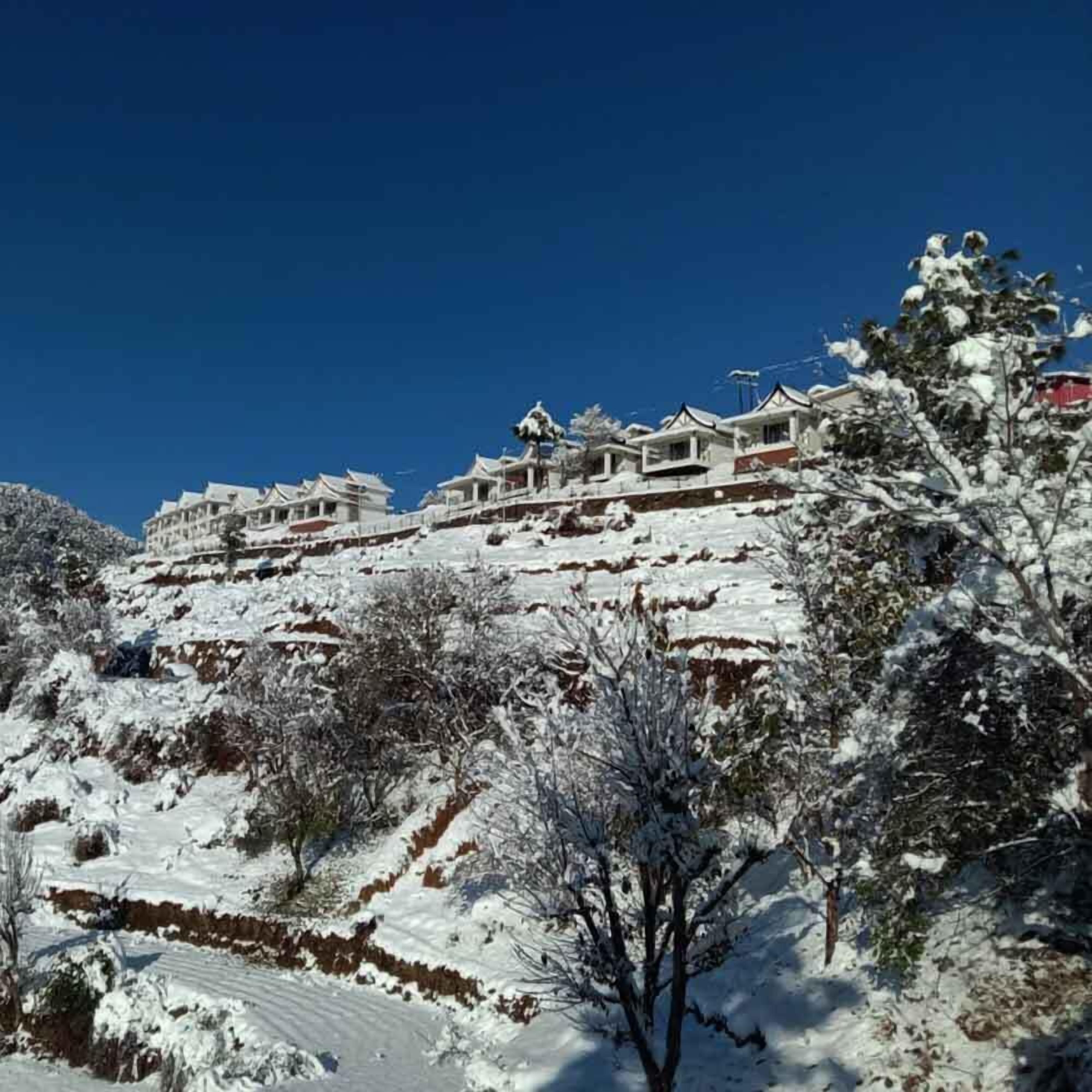 Hotel com arquitetura tradicional, situado numa encosta com paisagem coberta de neve.