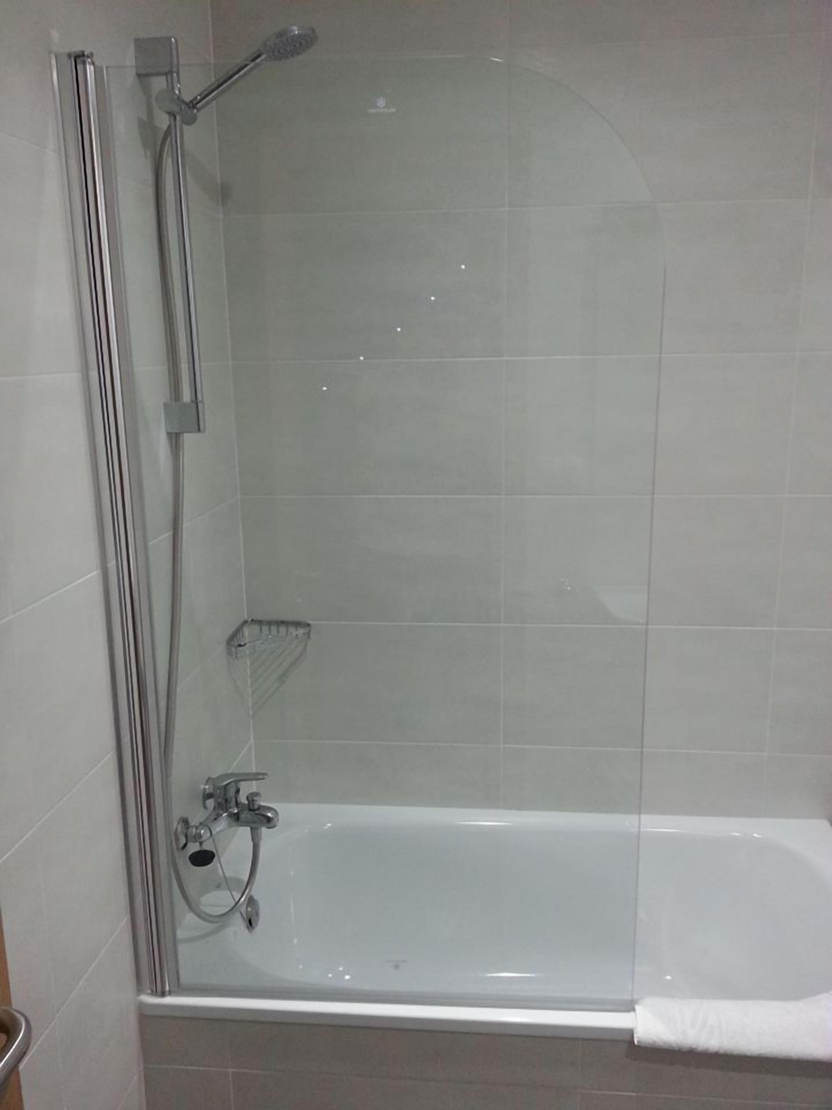 Uma casa de banho moderna com chuveiro em cabine de vidro, banheira e chuveiro de mão.