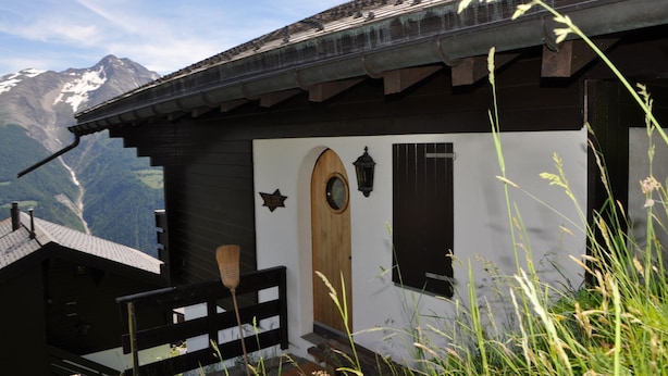 Um chalé com porta de madeira, decoração em forma de estrela e vista para as montanhas.