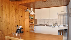 Uma cozinha com paredes de madeira, armários brancos e bancada de madeira.