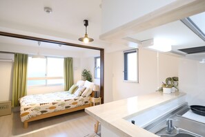 Quarto com cama, mesa de cabeceira e janela com cortinas.