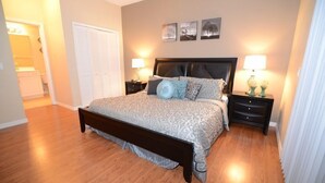 Quarto com uma cama grande, duas mesas de cabeceira e uma porta.