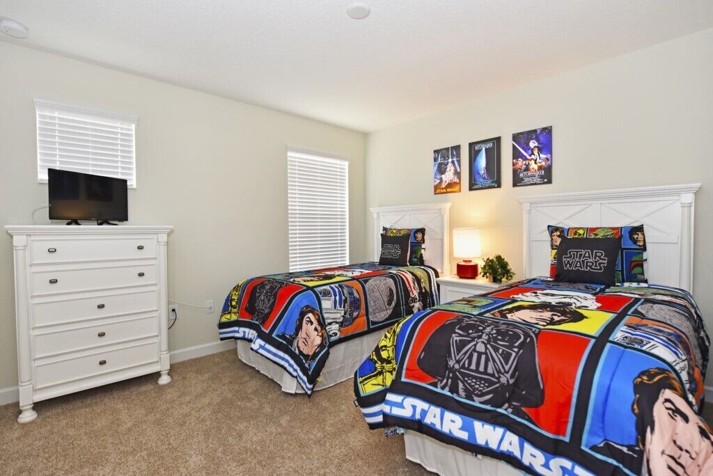 Quarto com duas camas, penteadeira e roupa de cama com tema de Star Wars.