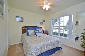 Quarto com uma cama grande, um ventilador de teto e janela com vista para o exterior.