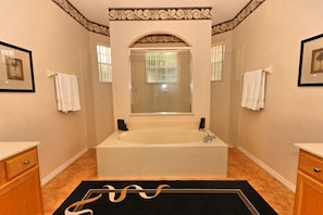 Uma casa de banho espaçosa com uma banheira grande, duas pias e um lavatório.