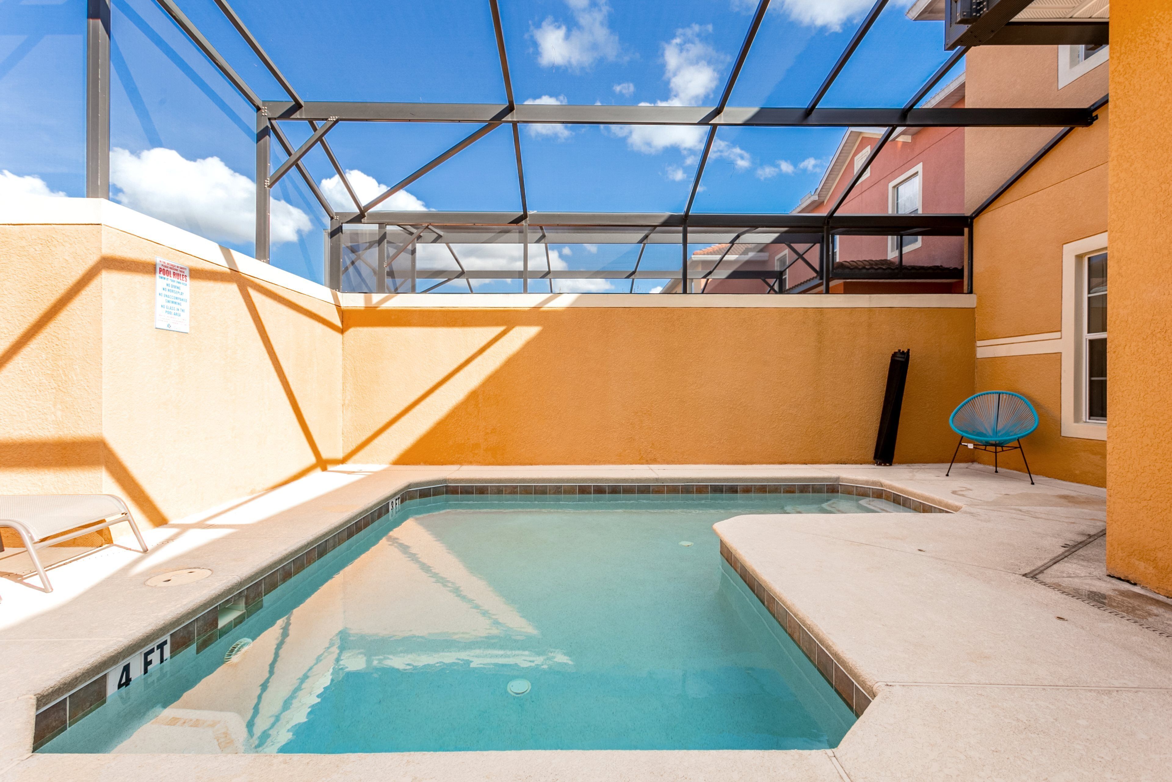 Piscina com cobertura de vidro, uma cadeira e placa indicando profundidade de 1,2 metros.