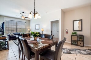Uma sala de jantar com uma mesa de mármore, cadeiras de couro e um ventilador de teto.