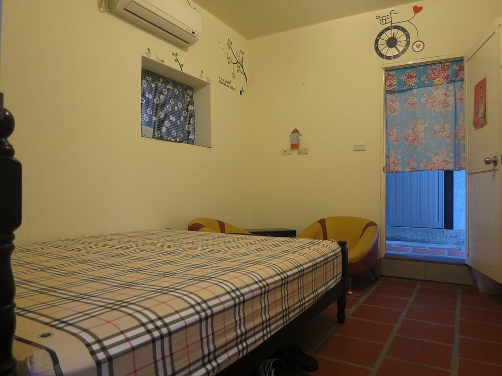 Um quarto com uma cama, uma cadeira, uma janela e uma porta.