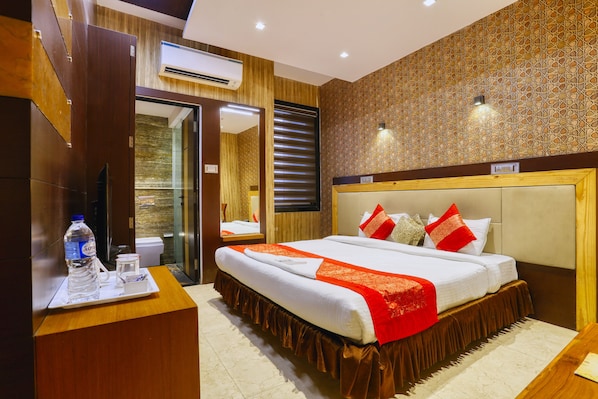 Quarto de hotel com cama grande, cabeceira de madeira, mesa de cabeceira e um espelho.