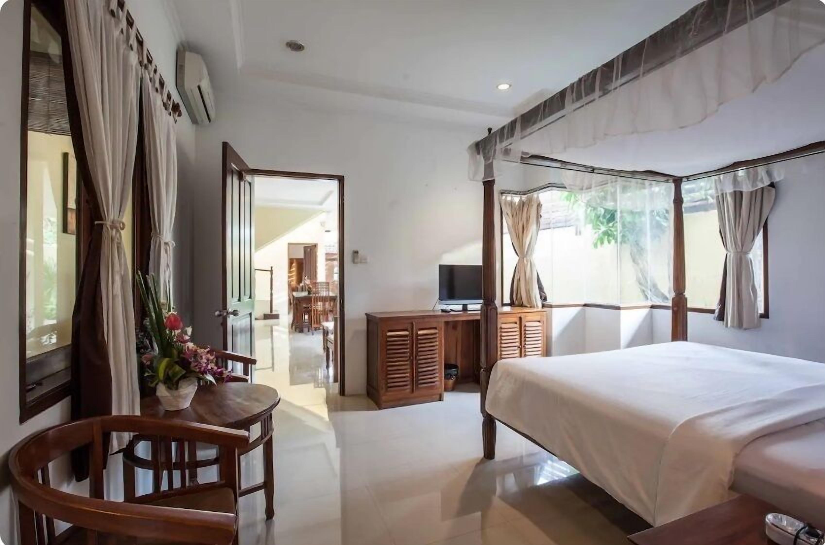 Quarto de hotel com cama, secretária, televisão e vista para o exterior.