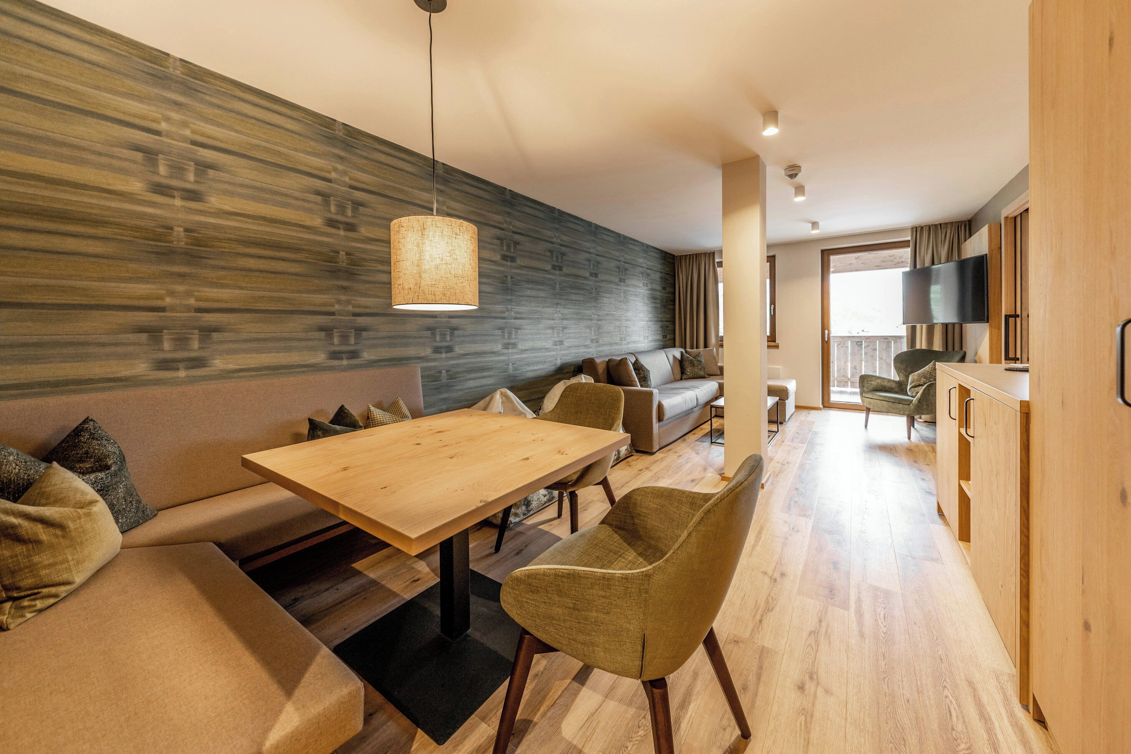 Uma sala de estar moderna com uma mesa de jantar de madeira, sofás e uma televisão.