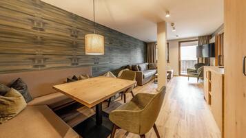 Uma sala de estar moderna com uma mesa de jantar de madeira, sofás e uma televisão.