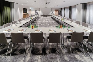 Uma sala de conferências com uma mesa comprida, cadeiras e piso coberto de carpete.