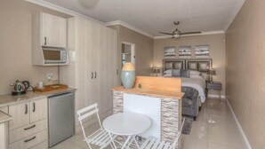 Quarto de hotel compacto com cozinha compacta, área de refeições e uma cama.