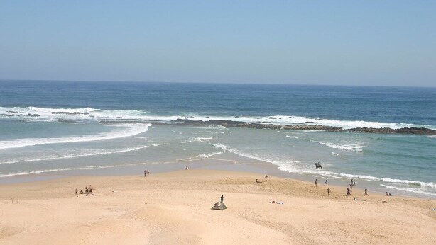 Uma praia com areal e ondas.