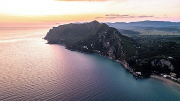 Paisagem costeira com uma montanha imponente, uma praia e um vale.
