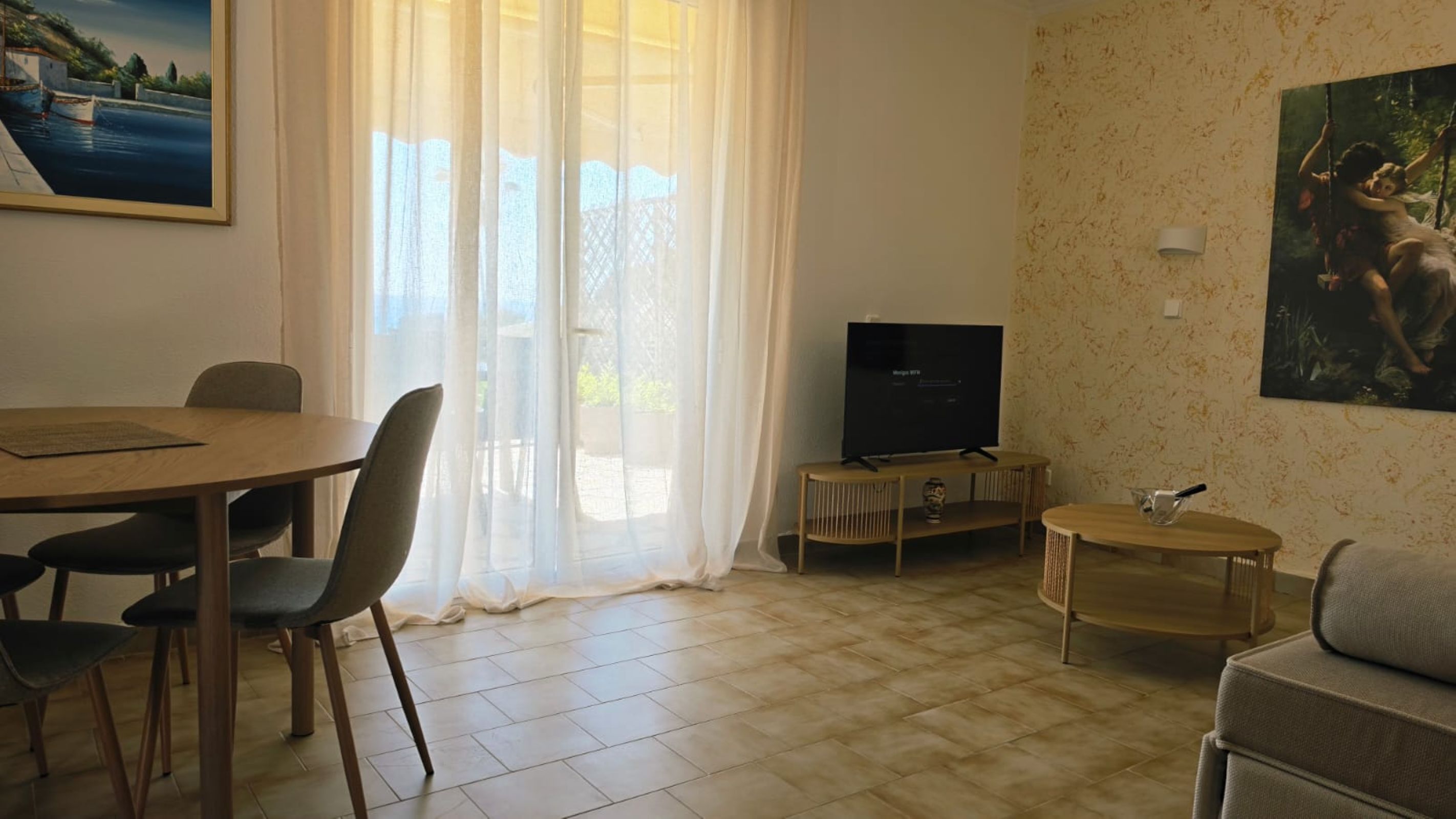 Uma sala de estar com uma mesa de jantar, cadeiras, uma televisão e um sofá.