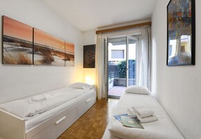 Quarto com cama, mesa de cabeceira e janela com cortinas.