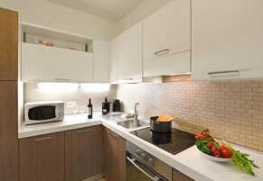 Uma cozinha moderna com armários brancos, micro-ondas, fogão e pia.