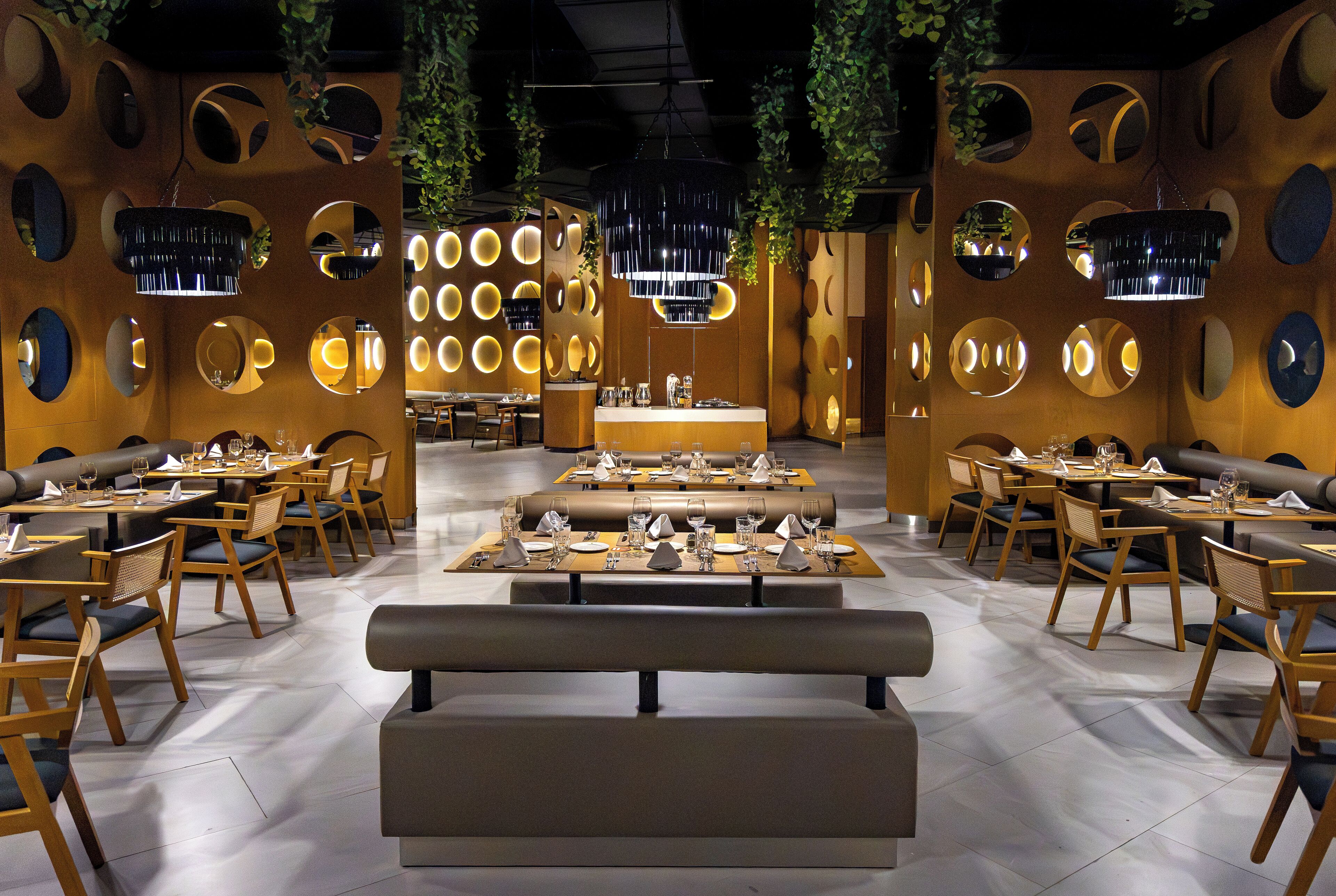 Um restaurante moderno com mesas redondas, cadeiras de madeira e um espaço de bar central.