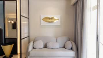 Uma sala de estar moderna com um sofá cinzento, um quadro abstrato dourado e um espelho.