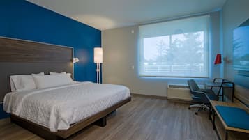 Quarto de hotel moderno com uma cama grande, uma escrivaninha e uma cadeira.