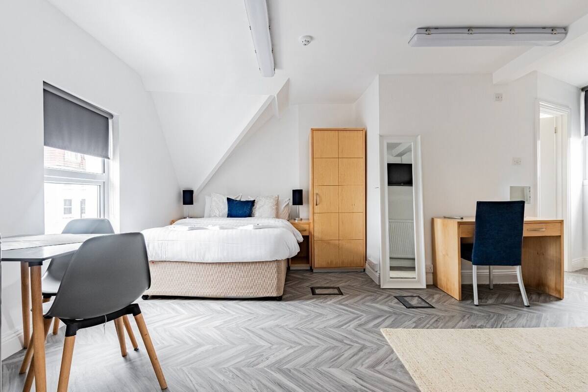 Quarto moderno com cama, escrivaninha e cadeira, piso com padrão losango e guarda-roupa de madeira.